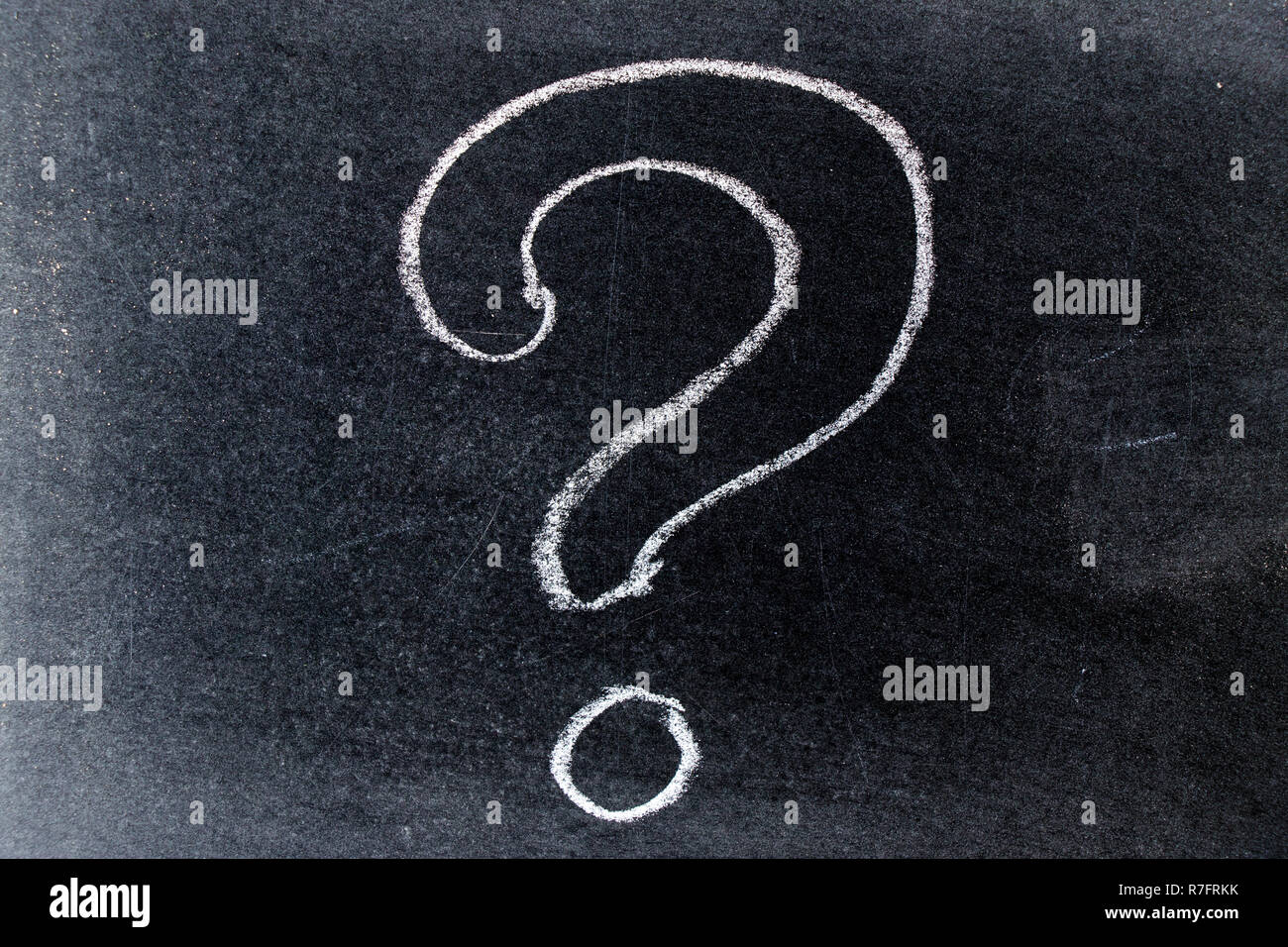 White chalk drawing in questionmark shape on black board background ...