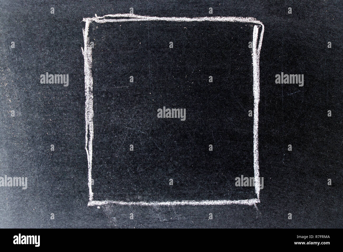 White chalk drawing in blank square shape on black board background ...