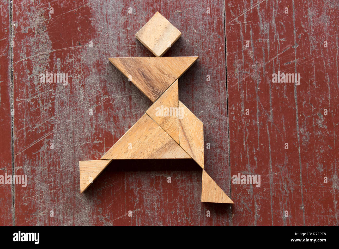 Tangram puzzle in joyful man running shape on red old wood background ...