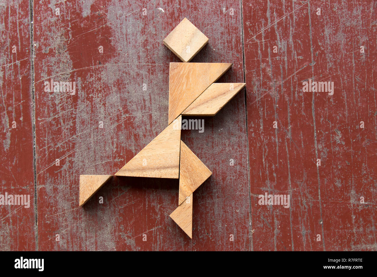 Tangram puzzle in joyful man running shape on red old wood background ...