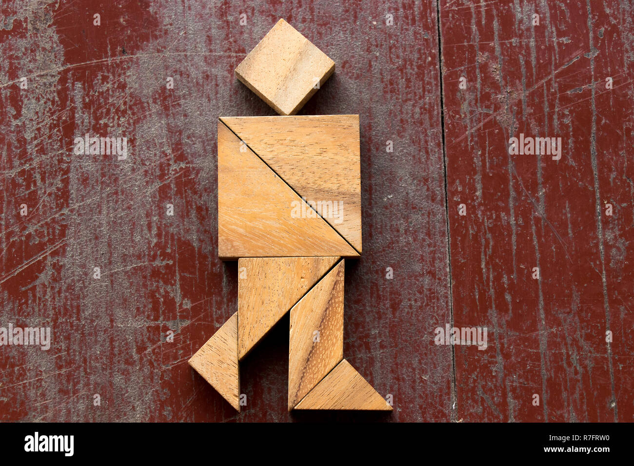 Tangram puzzle in man walking shape on red old wood background Stock ...