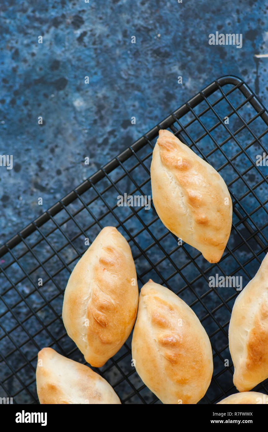 Small mashed potato pasties (hand pies) on a wire rack. Blue sto Stock ...