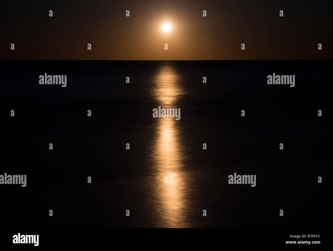A rising full moon reflecting in the sea Stock Photo - Alamy