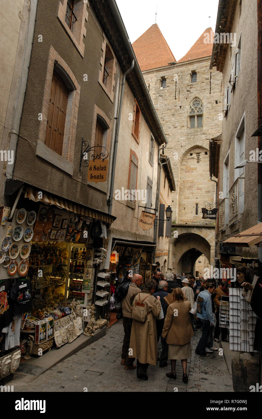 Tourists in a main narrow medieval street lined with tourist shops ...