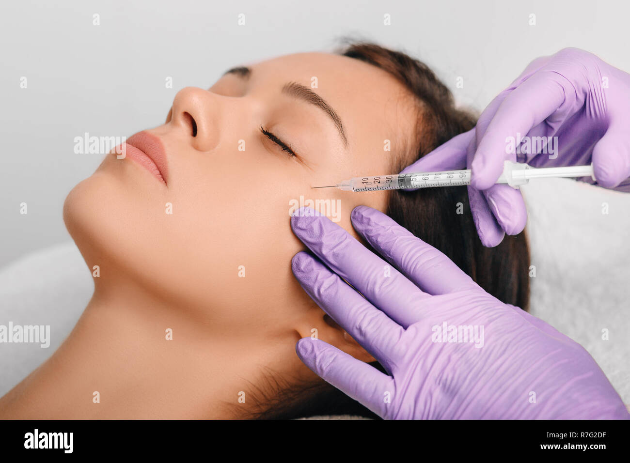 Woman receiving Botulinum Toxin Injection injection into eyes area ...