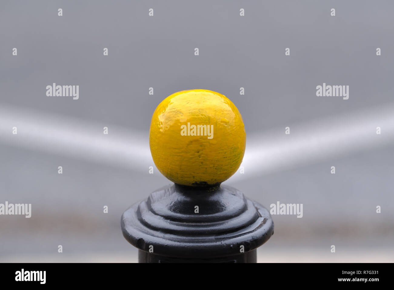 single yellow metal ball on parking pole, blurred street in the ...
