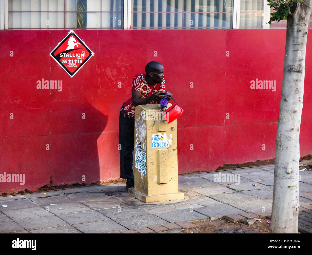 Man leaning against a pole in Johannesburg street, South-Africa Stock ...