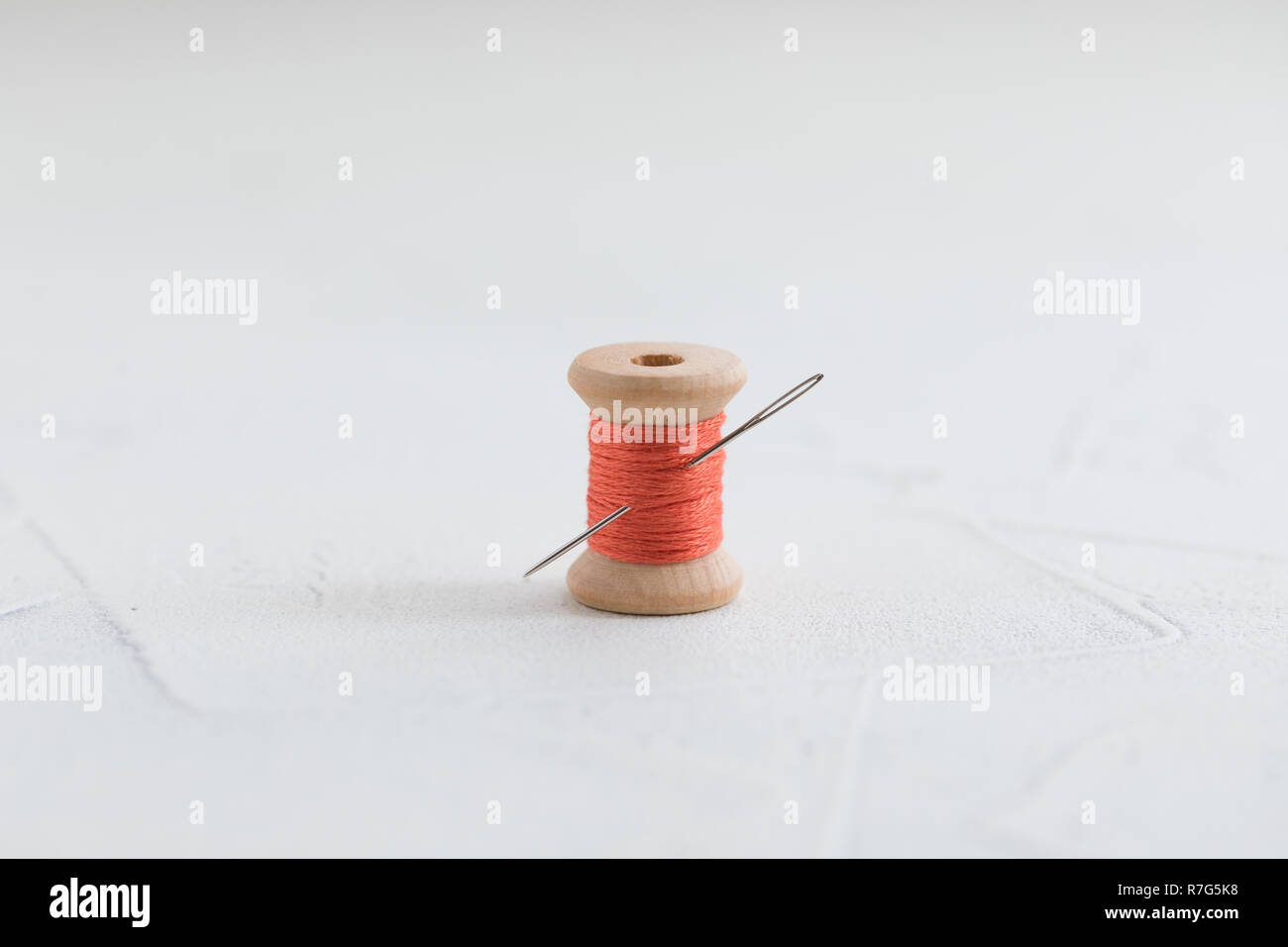 Trendy coral colored threads wooden bobbin for stitching with a needle ...