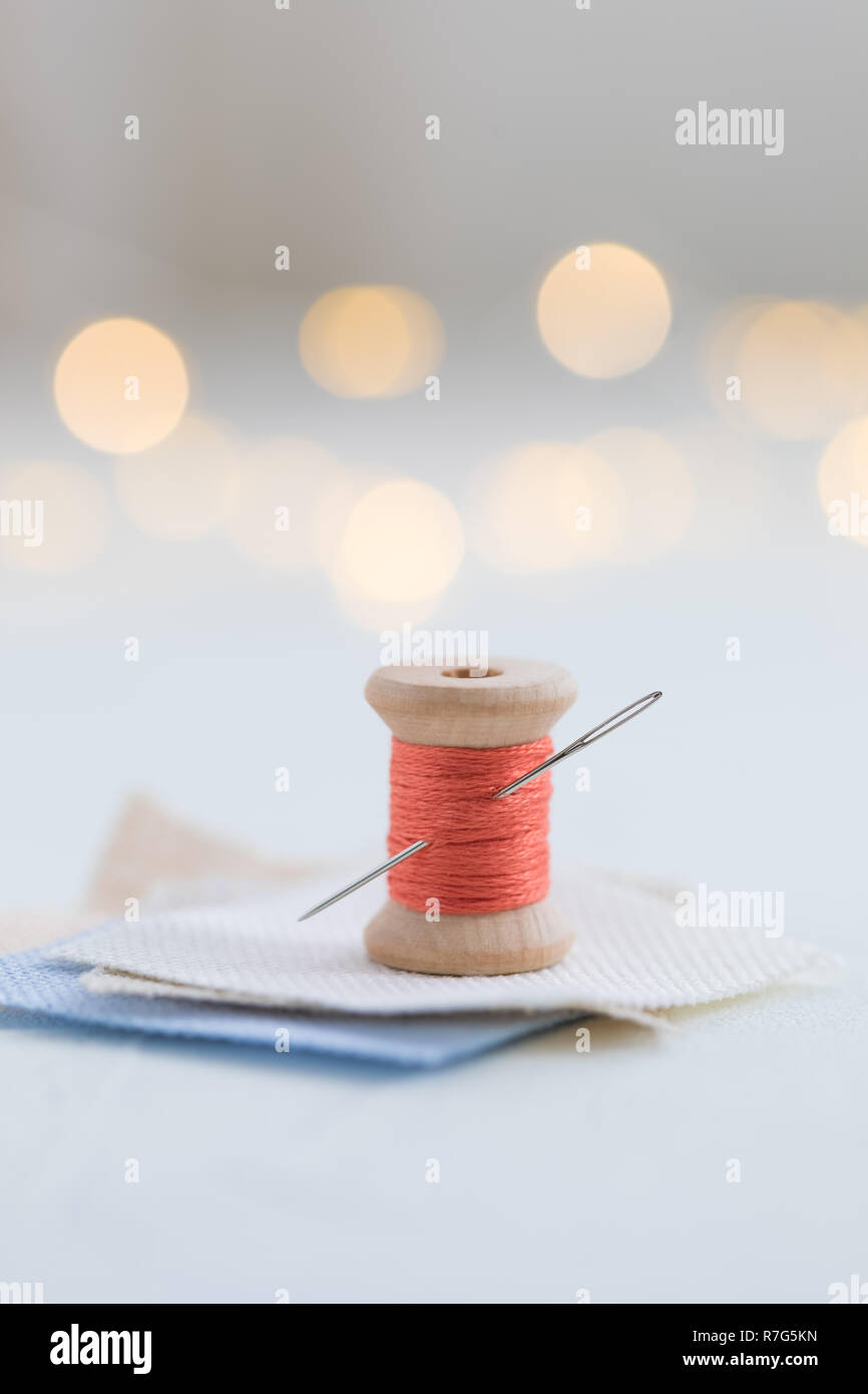 Trendy coral colored threads wooden bobbin for stitching with a needle ...