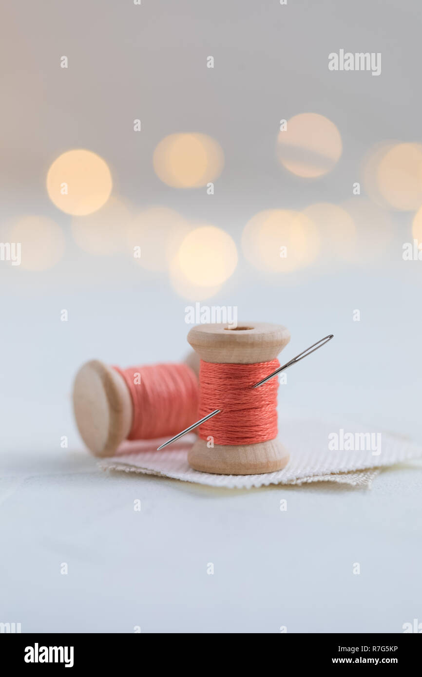 Trendy coral colored threads wooden bobbin for stitching with a needle ...
