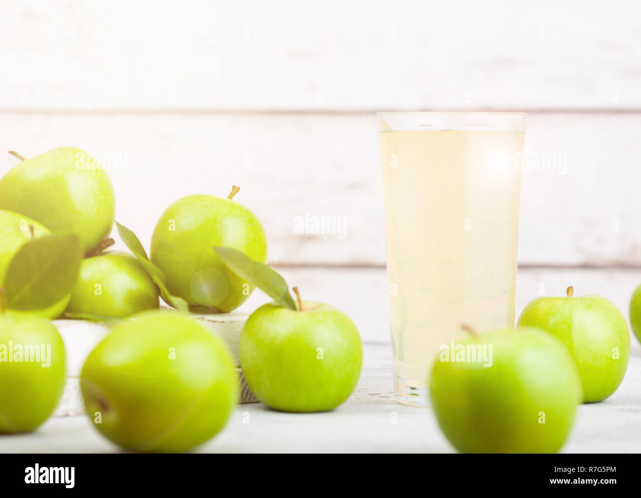 Glass of fresh organic apple juice with green apples in box on wooden ...