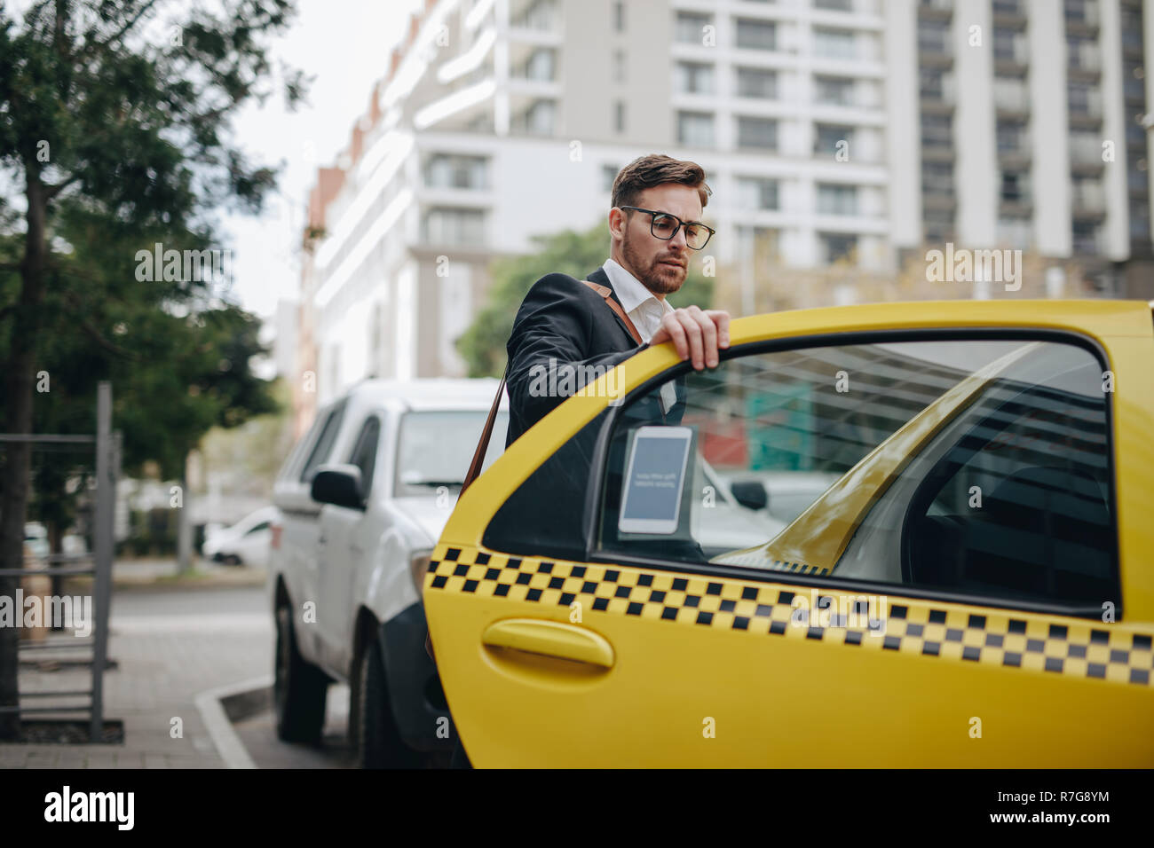 Businessman taking a taxi to commute to office. Man holding the door of ...
