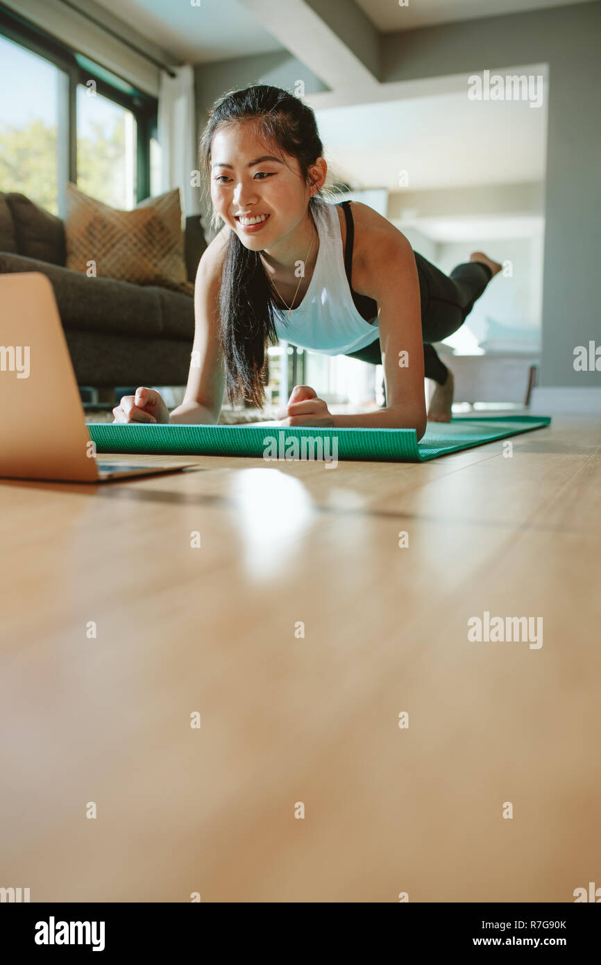 Fit young woman in plank position repeating online instructions by ...