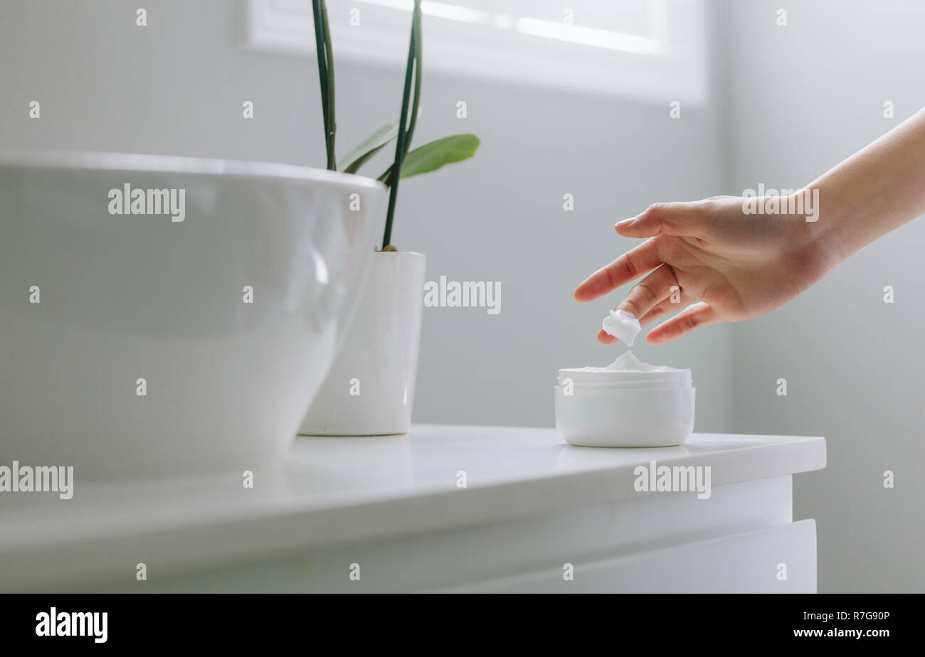 Close up of female hands taking moisturizing cream from bottle in ...