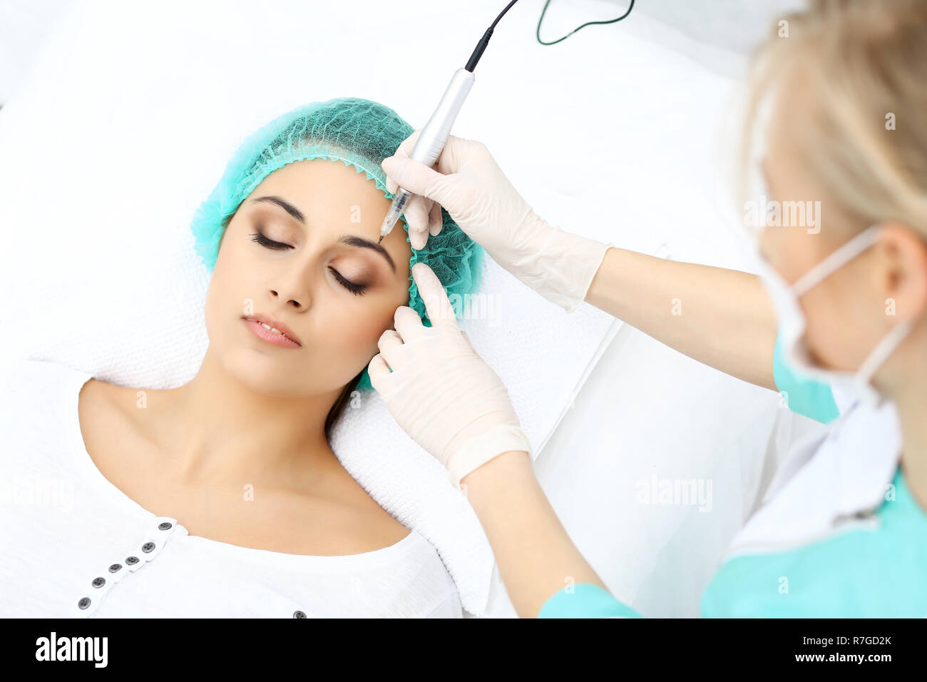 Professional beautician doing eyebrow tattoo at woman face. Permanent ...