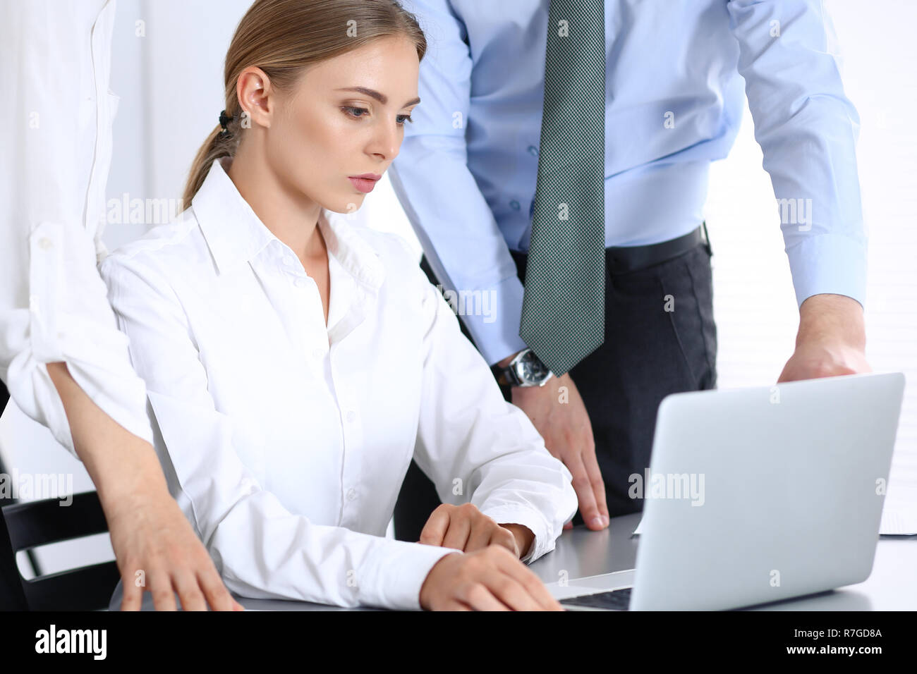 Group of business people using laptop computer while standing in office ...