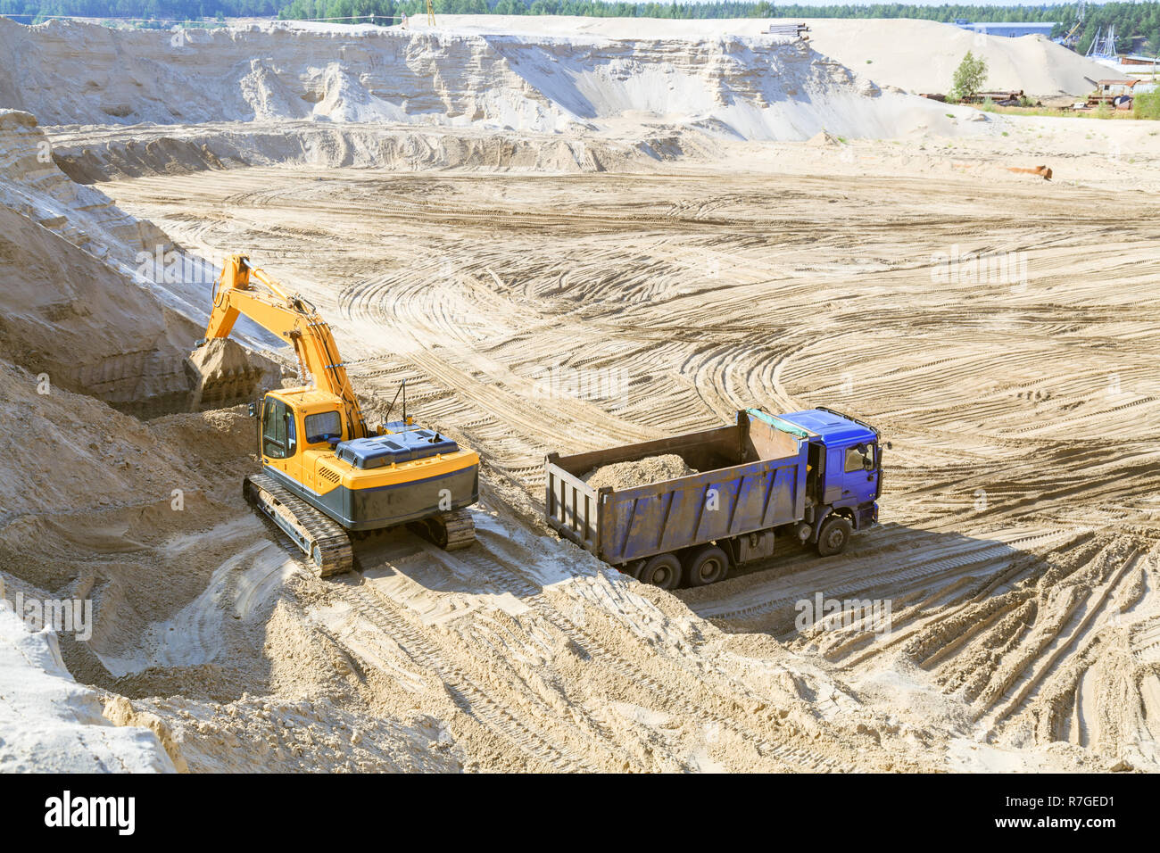 Work of the excavator and truck at a sand quarry. Excavator loading ...