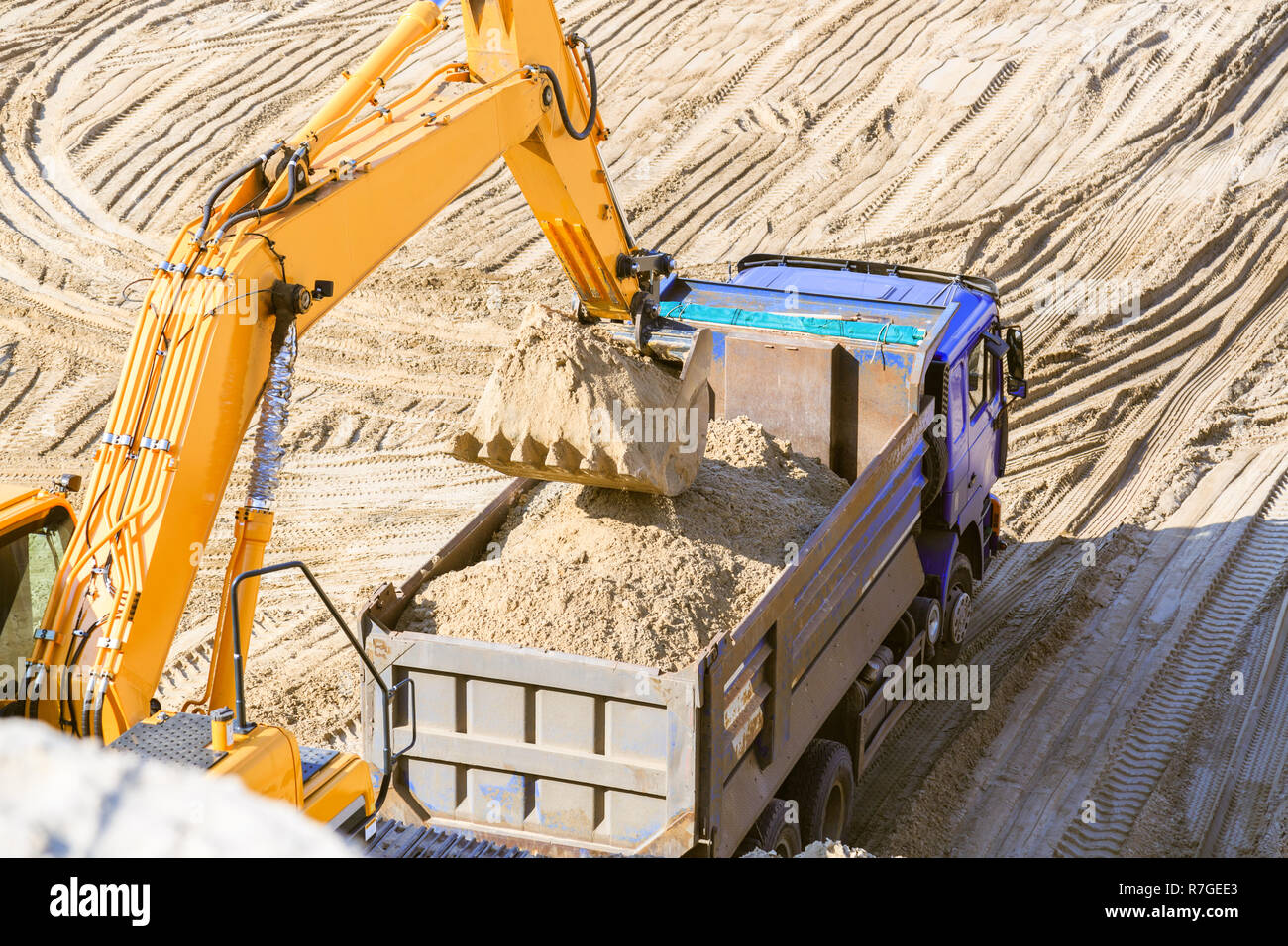 Work of the excavator and truck at a sand quarry. Excavator loading ...