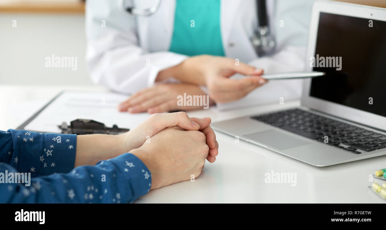 Close-up of a doctor and patient sitting at the desk while physician ...