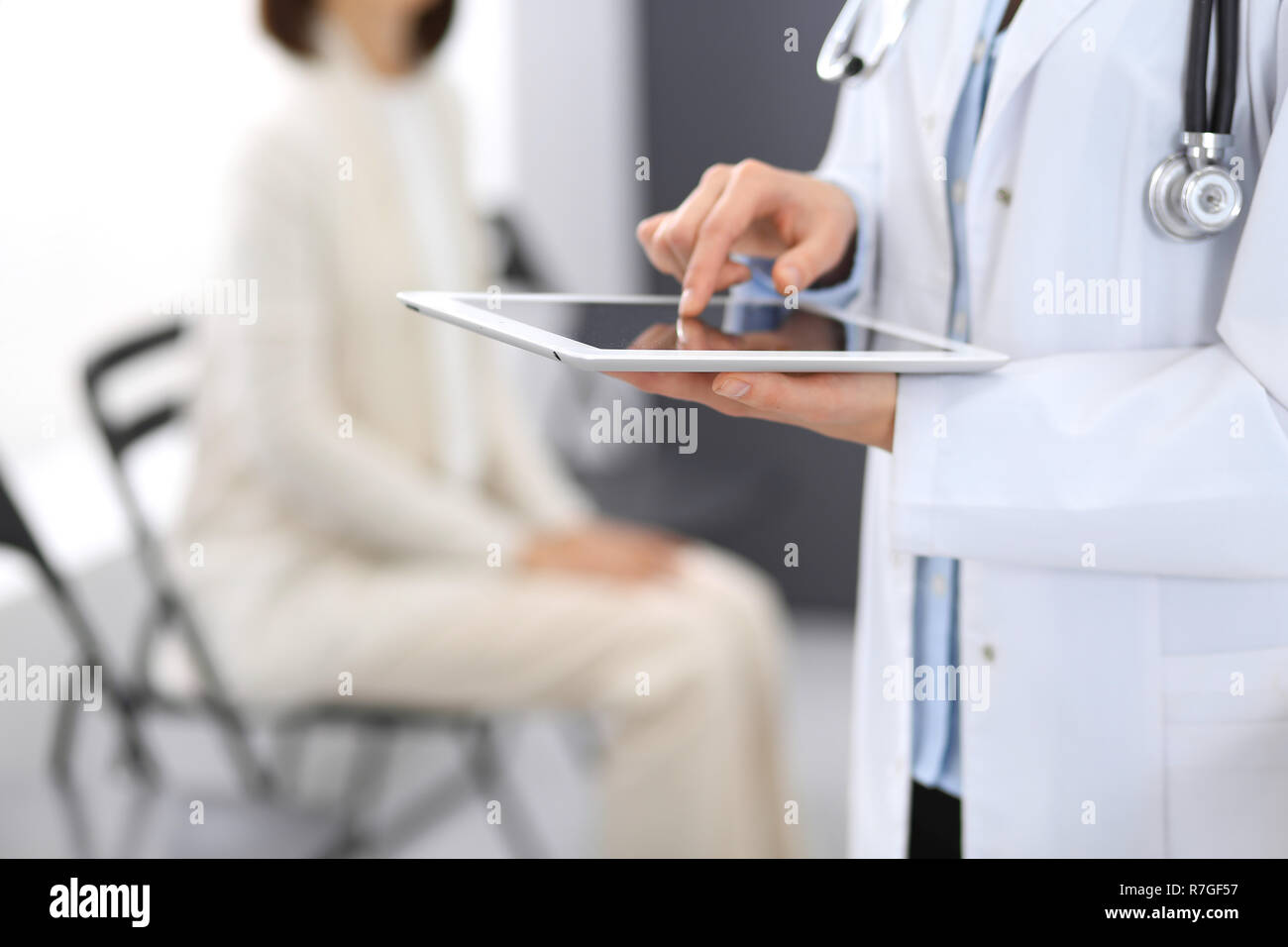 Female doctor woman using digital tablet while standing near reception ...