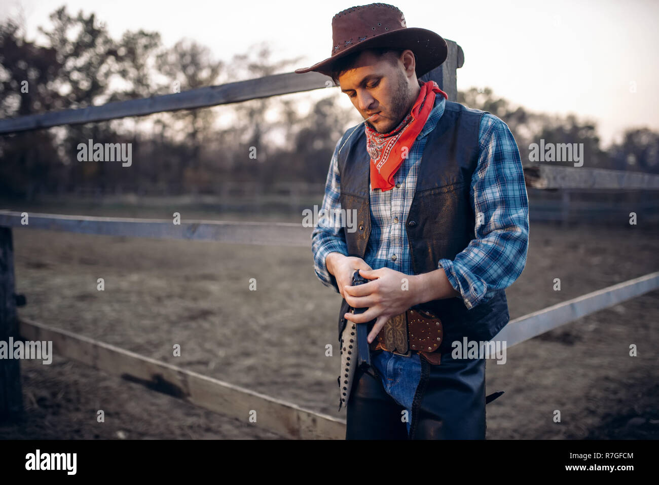 Cowboy checks his revolver before gunfight on ranch, western. Vintage ...