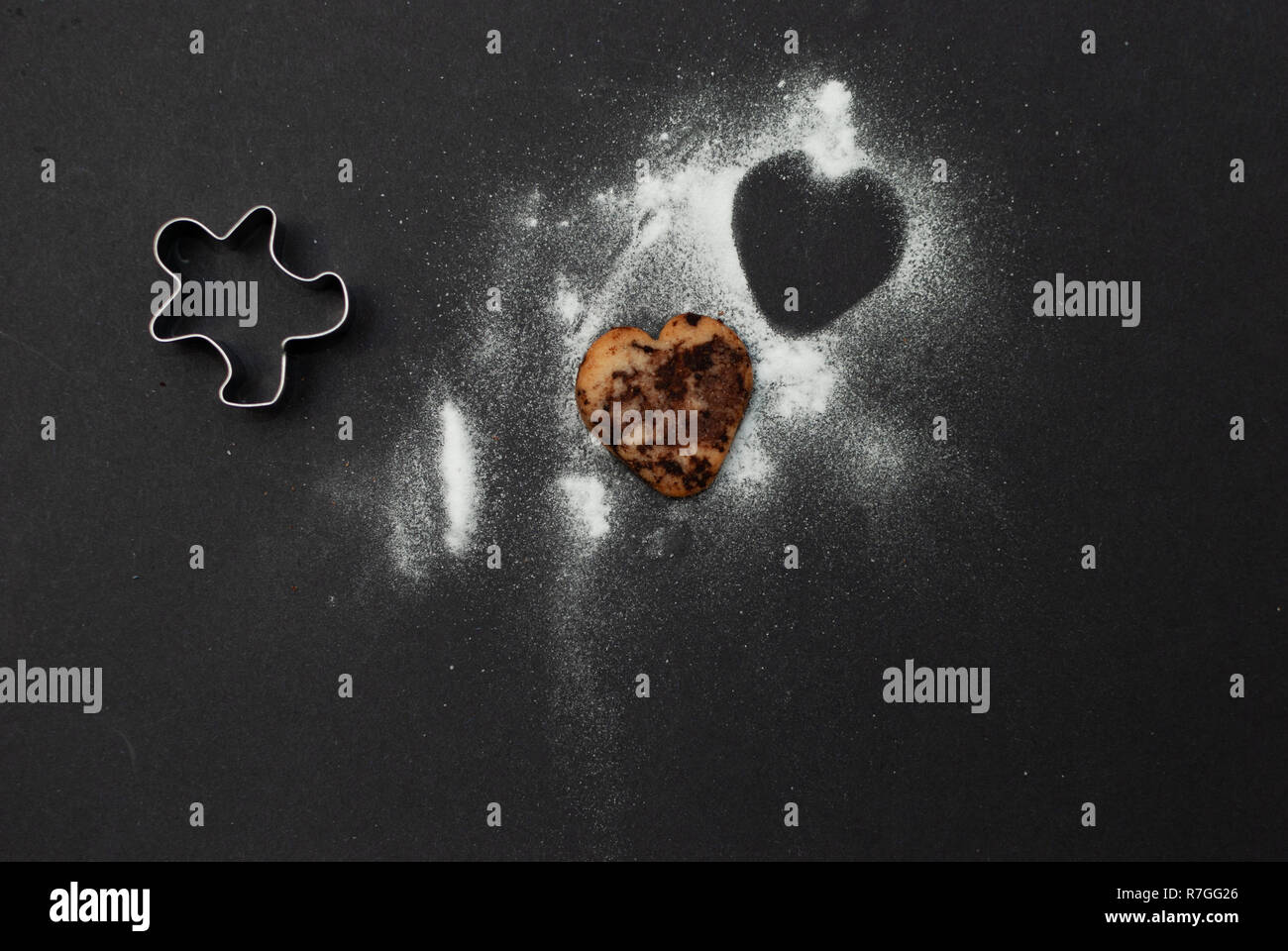 A baking form, a heart shaped cookie and a negative of the heart in ...