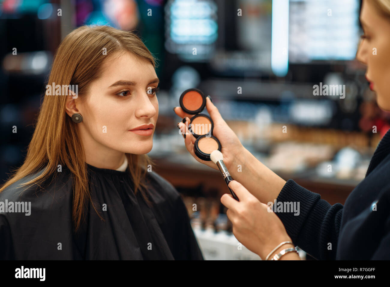 Cosmetician and female client in makeup shop. Female client and ...