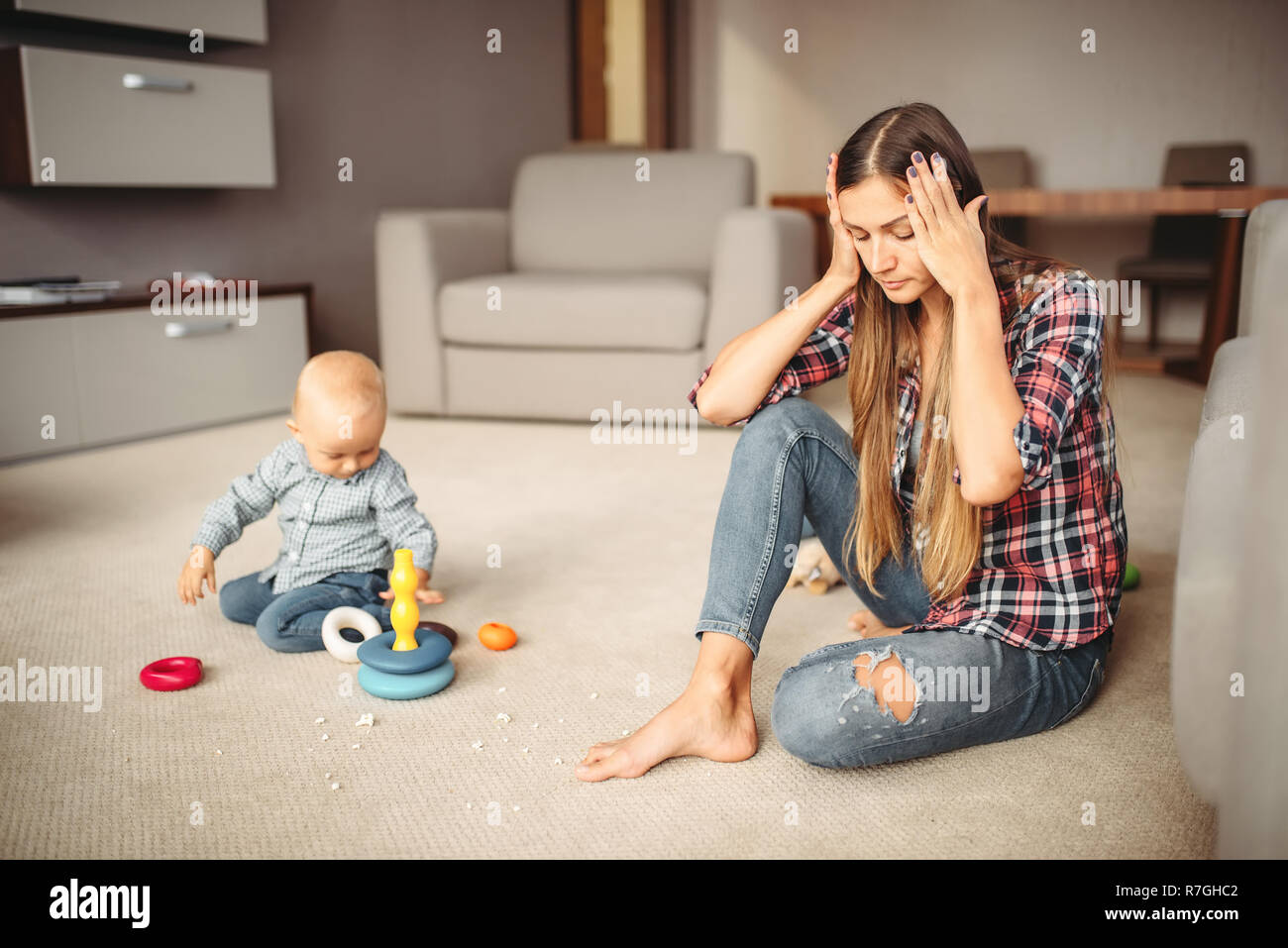 Stressed mom and son together at home, parenthood. Little kid playing ...