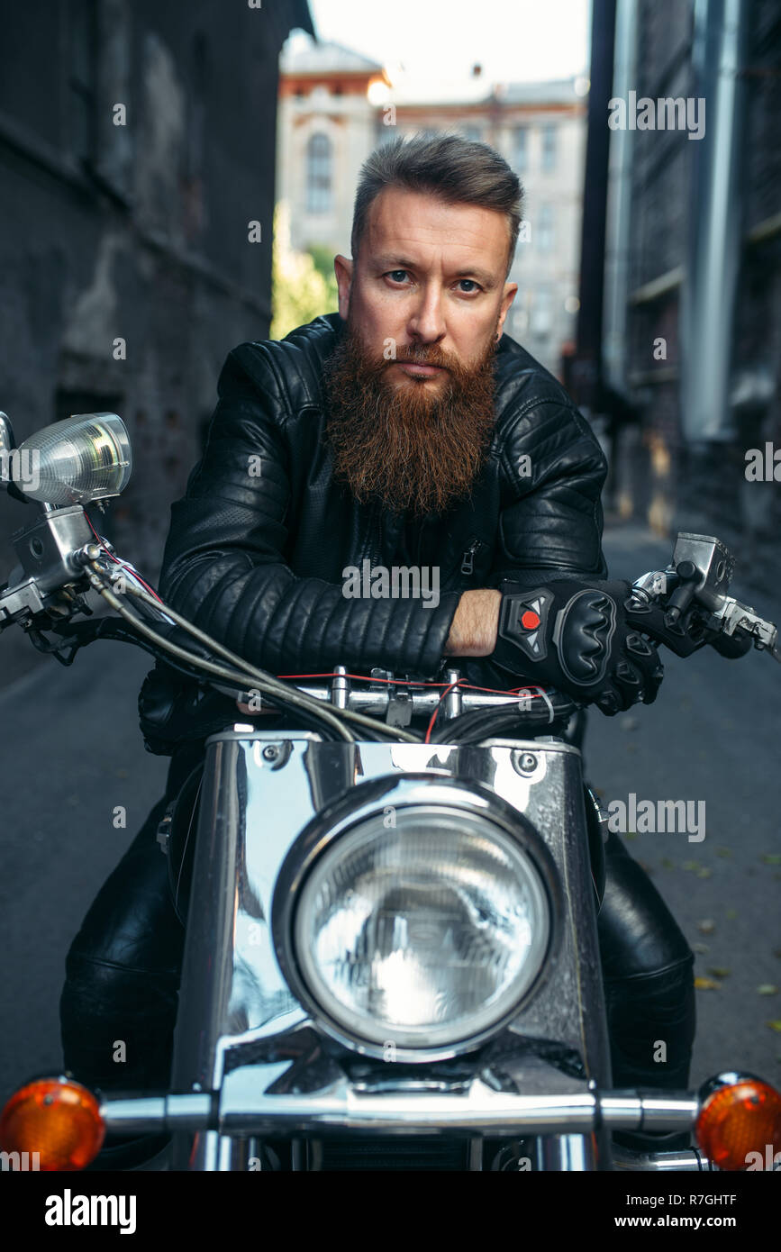 Bearded biker in leather jacket sitting on classical chopper, front ...