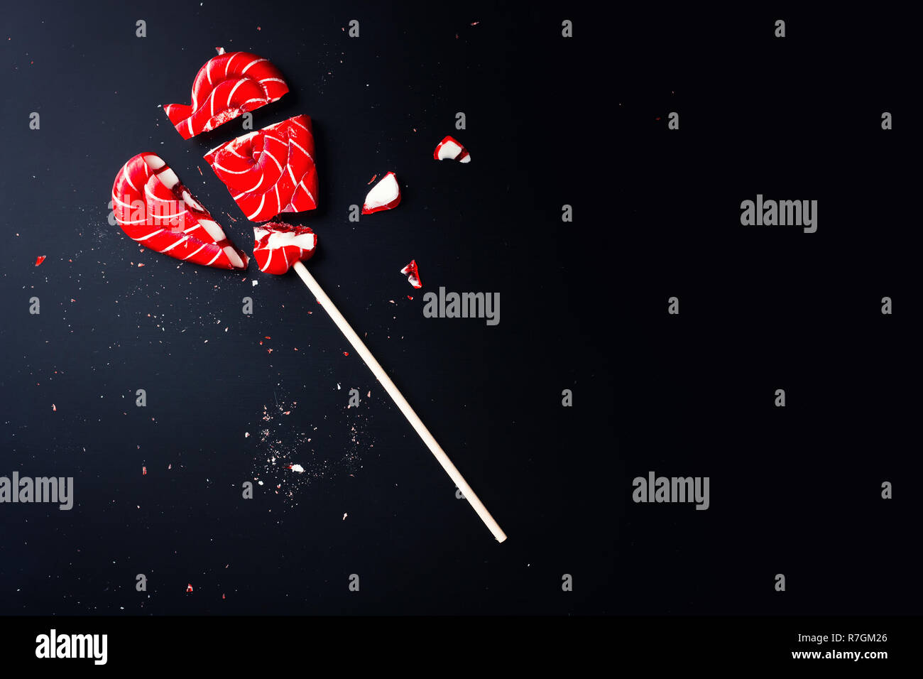 Broken lollipop in shape of heart on dark background with copy space ...
