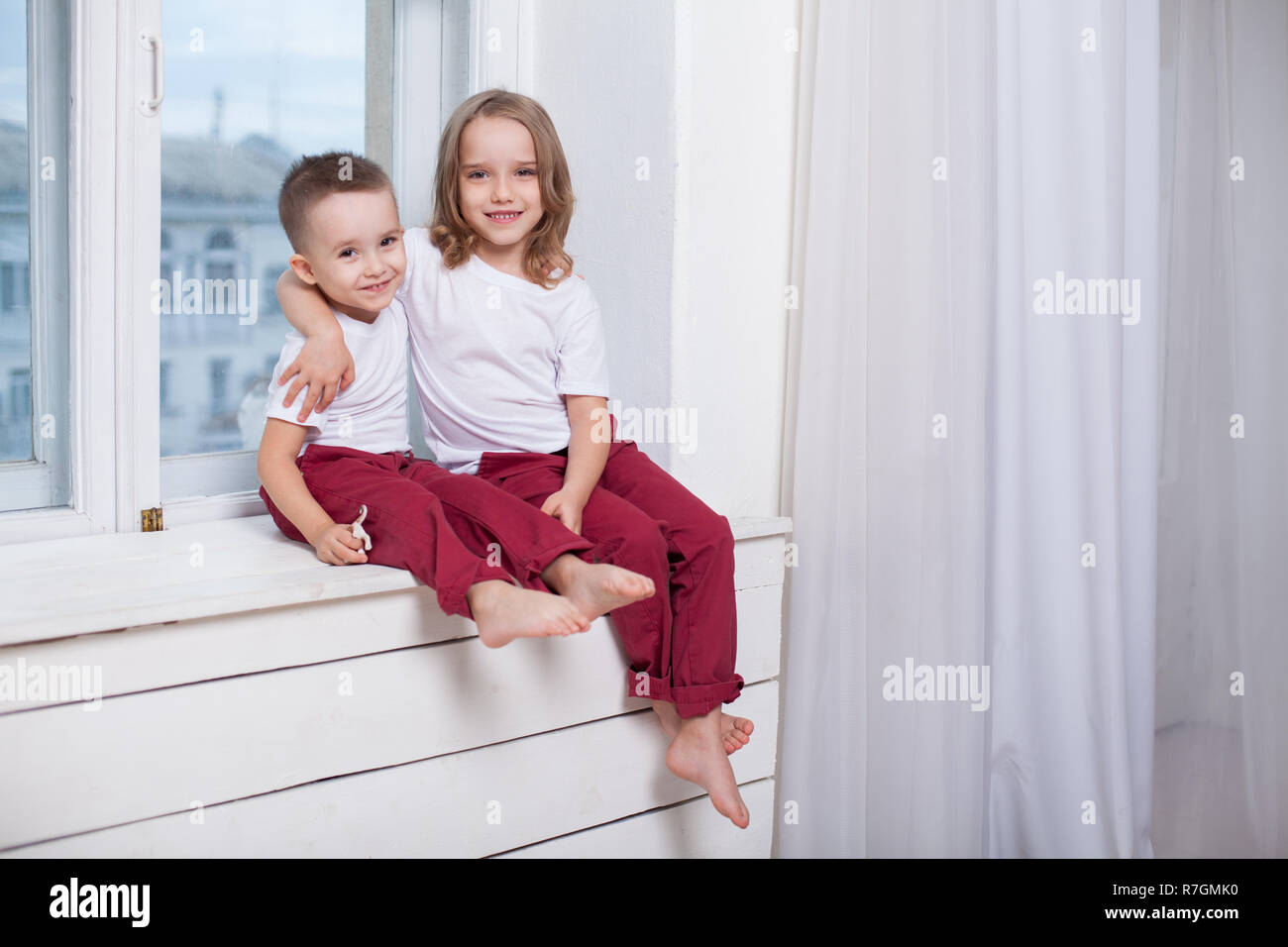 little boy and girl sit on the windowsill looking out the window Stock ...