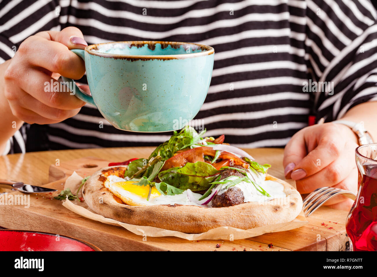 young woman is having a traditional english breakfast with bacon and ...