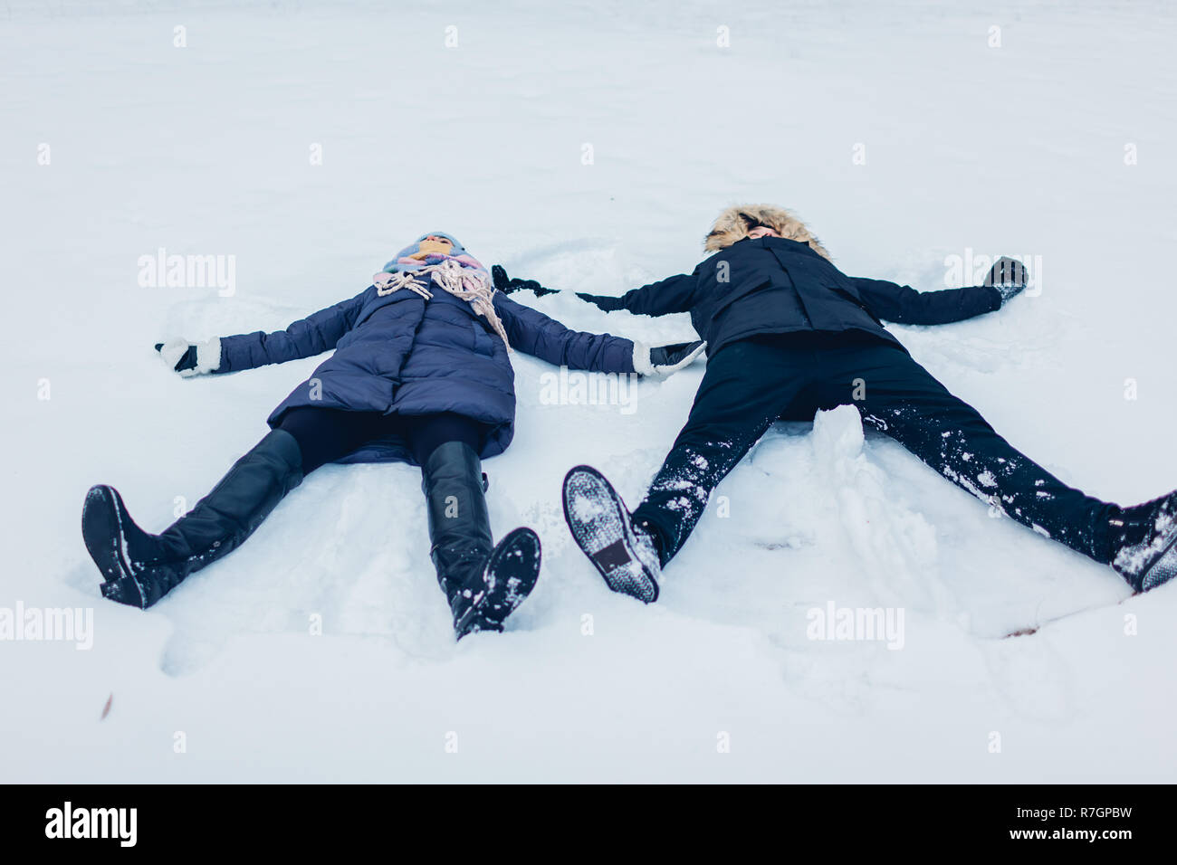 Beautiful loving couple making snow angels in winter forest lying in ...