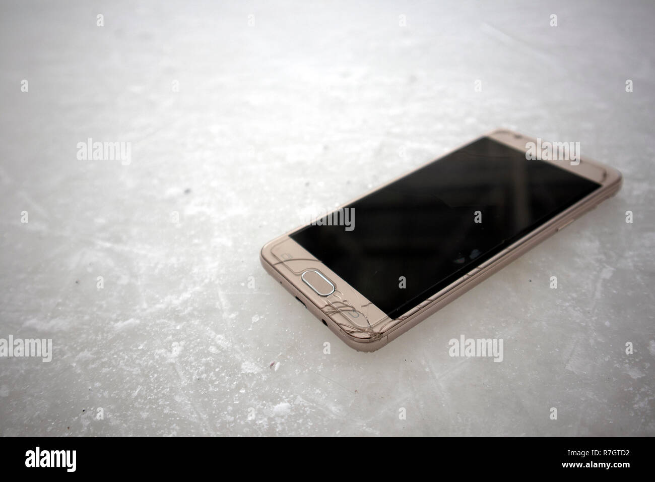 Modern smart phone with cracked screen glass lying on scratched ice ...