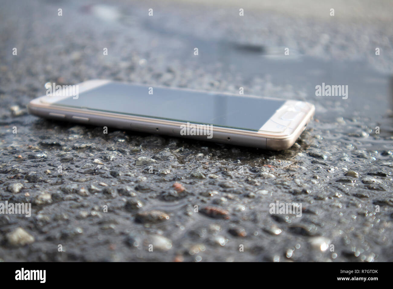 Modern smart phone with cracked screen glass lying in a puddle on the ...