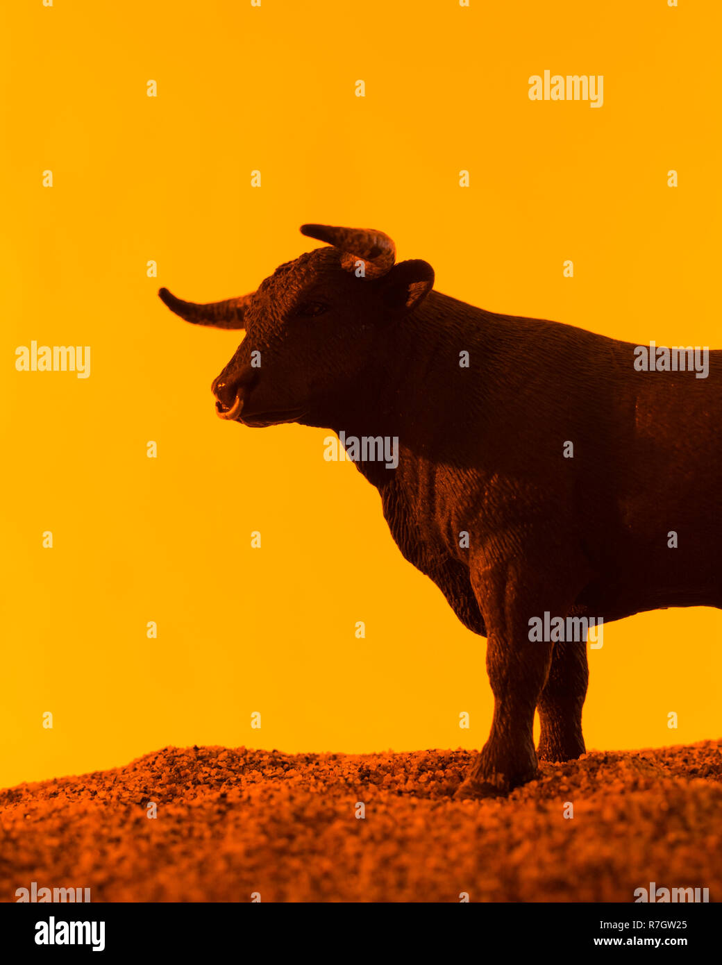 Toy bull against orange-yellow glowing sunset type backdrop. Metaphor ...