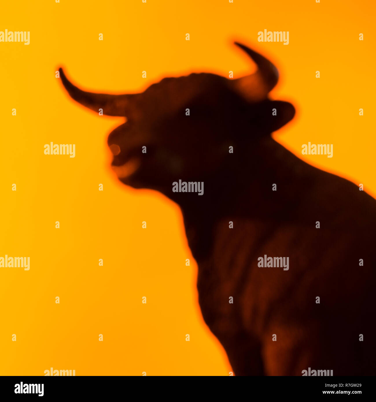 Toy bull against orange-yellow glowing sunset type backdrop. Metaphor ...