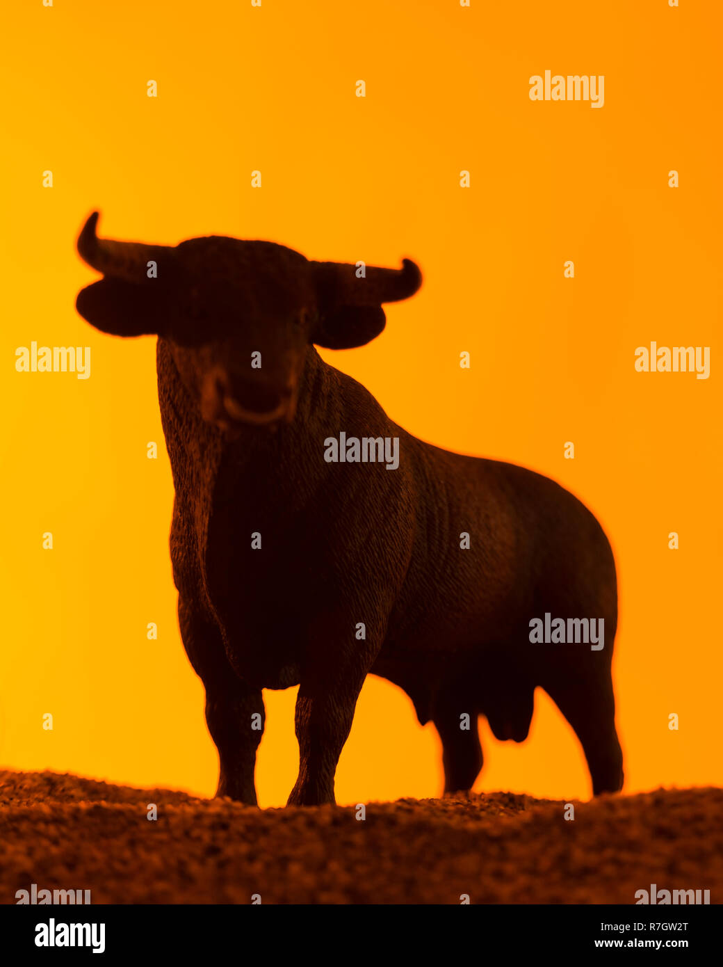 Toy bull against orange-yellow glowing sunset type backdrop. Metaphor ...
