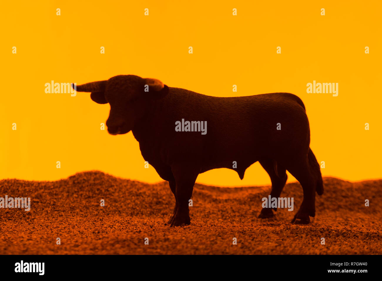 Toy bull against orange-yellow glowing sunset type backdrop. Metaphor ...