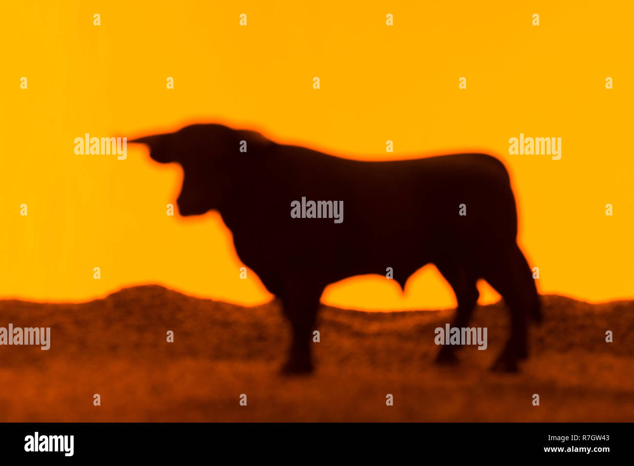 Toy bull against orange-yellow glowing sunset type backdrop. Metaphor ...