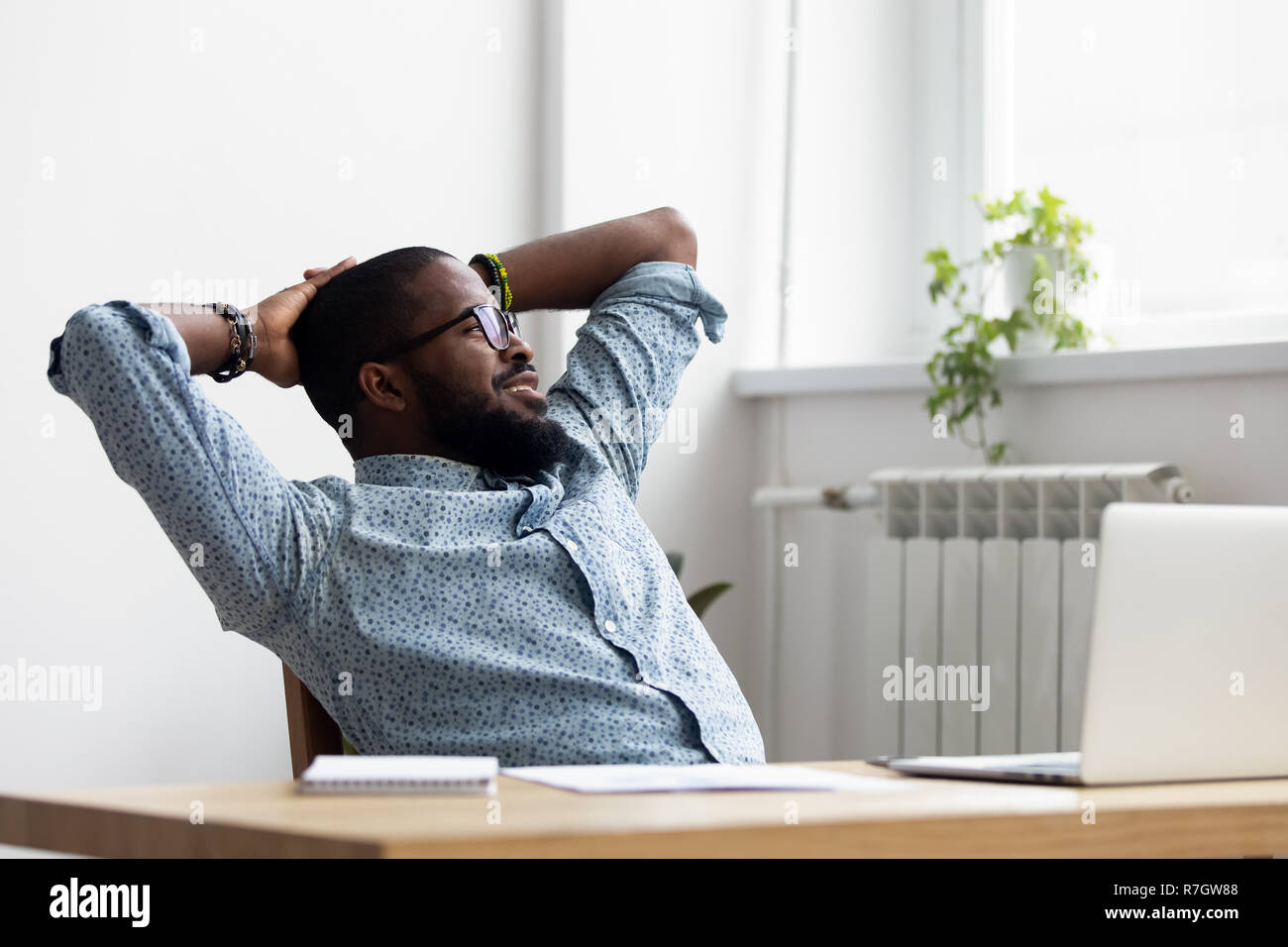 Black relaxed worker sitting on chair looking at window Stock Photo - Alamy