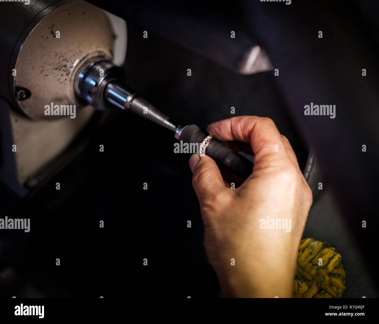 Jeweler polishes a gold ring on a bench grinder in an authentic ...