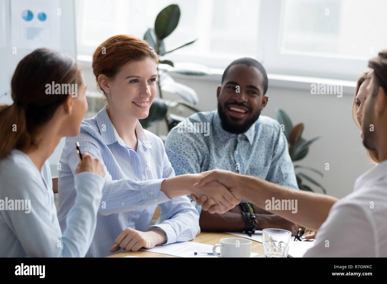 Multi-ethnic businesswoman shaking hands greeting company client Stock ...