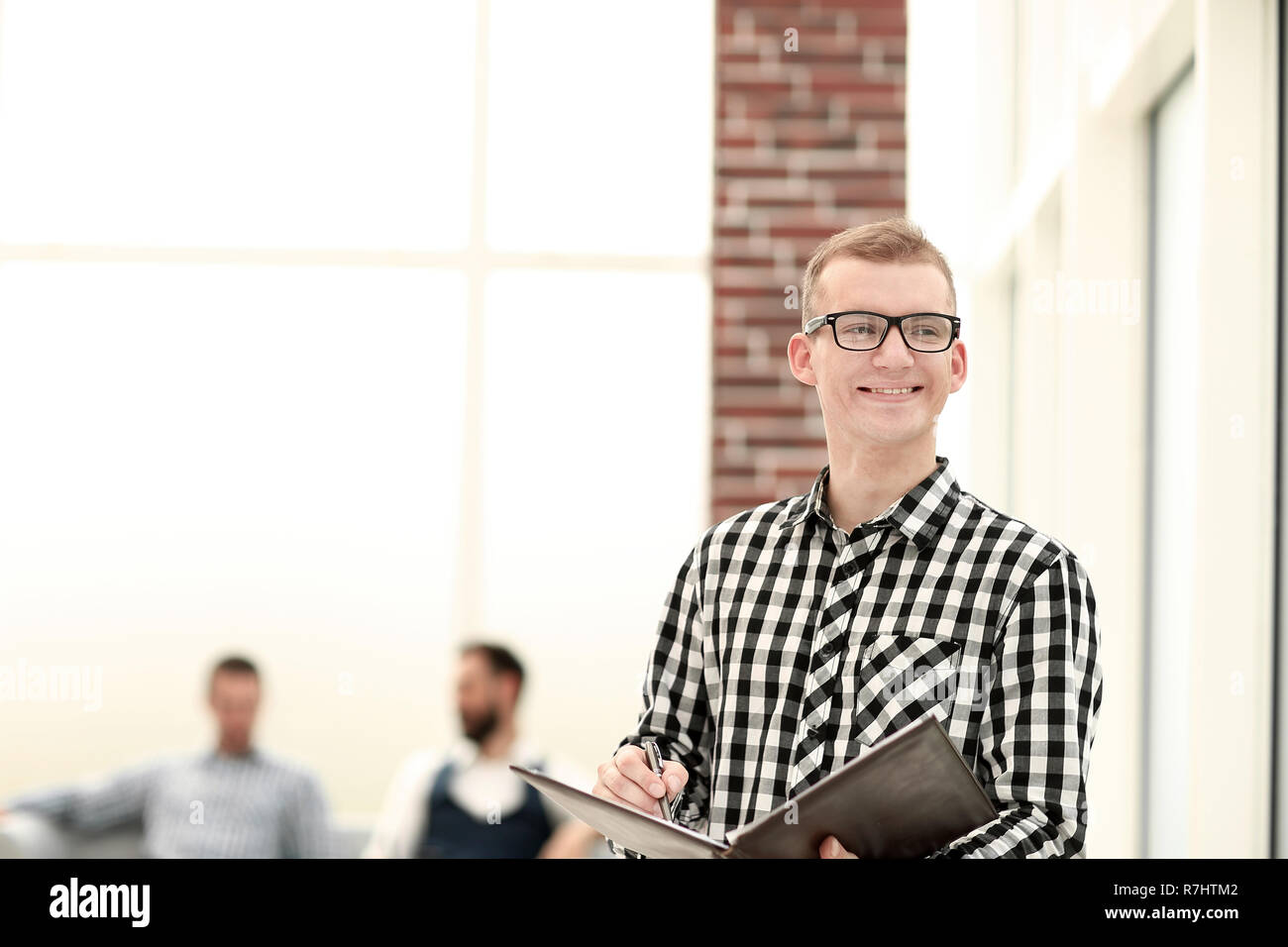 smiling employee with a clipboard standing in the office Stock Photo ...