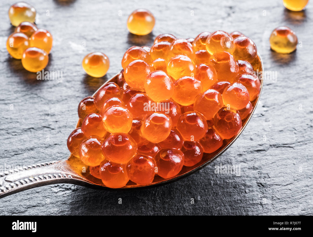 Silver spoon of red caviar on gray graphite background. Macro picture ...