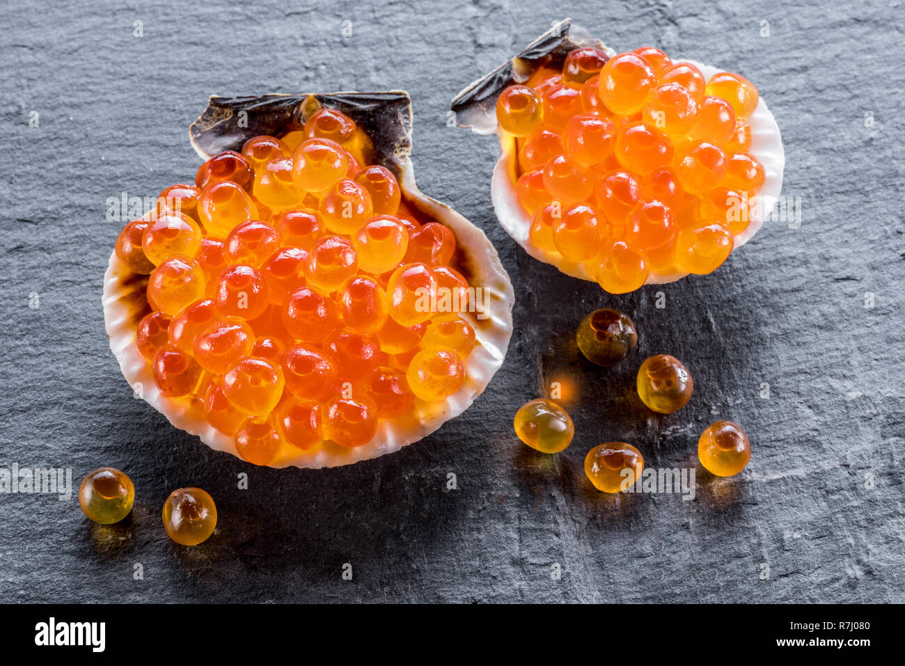 Red caviar in the sea shells on gray graphite background. Macro picture ...