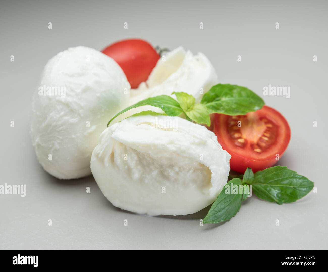 Traditional Italian mozzarella cheese with herbs and tomatoes on gray ...