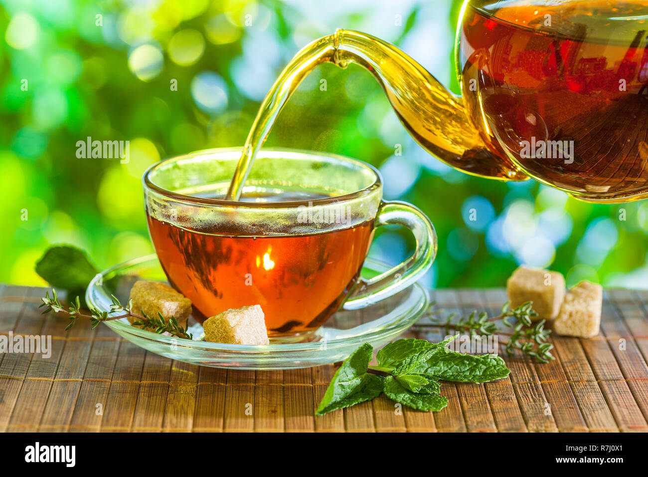 Tea time. Pouring out hot tea into a cup. Green nature background Stock ...