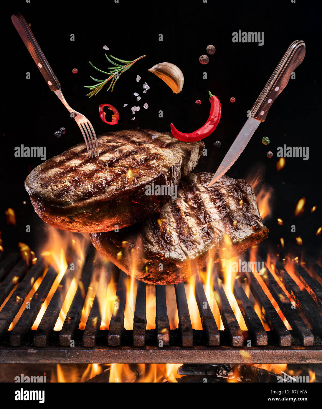 Beef steaks with spices fly over the blazing grill barbecue fire ...