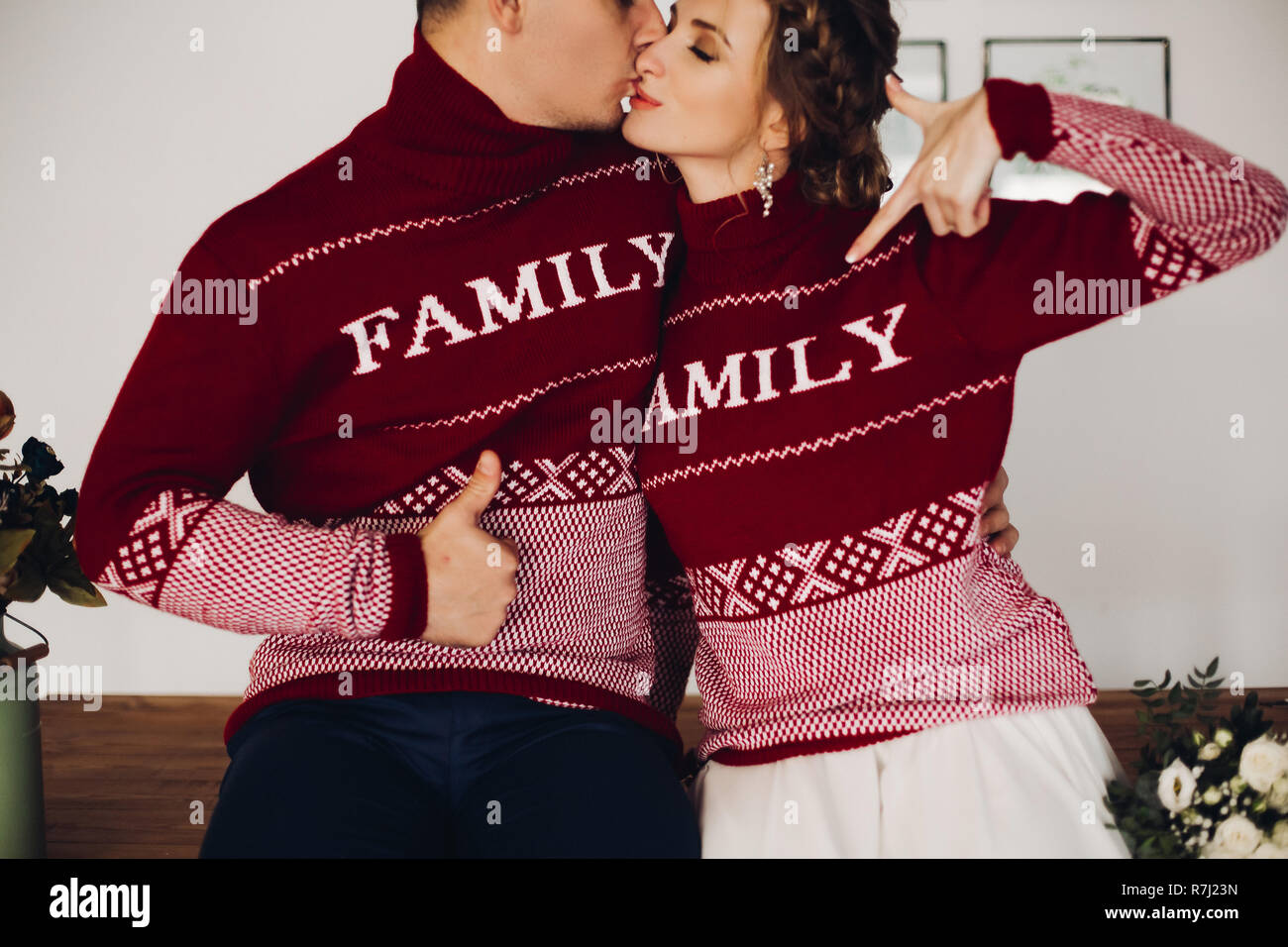 Couple in red sweaters having fun together and pointing by fingers ...